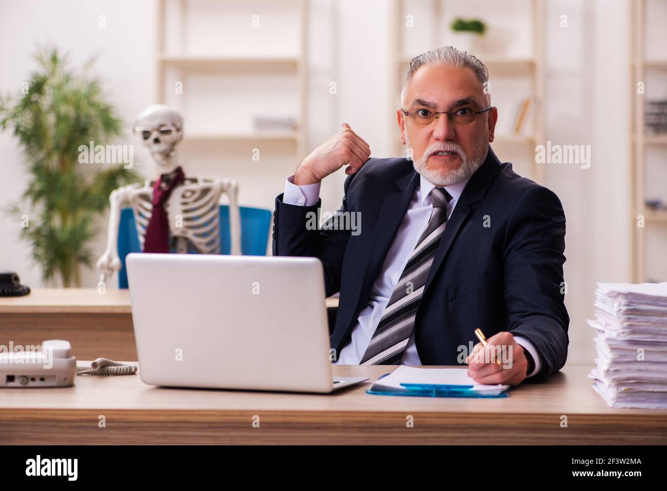 Dead employee working in the office in funny concept Stock Photo - Alamy