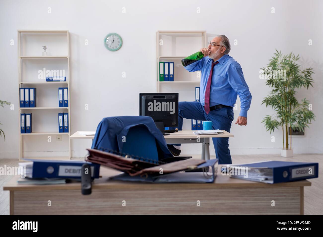 Senior male employee drinking alcohol in the office Stock Photo - Alamy