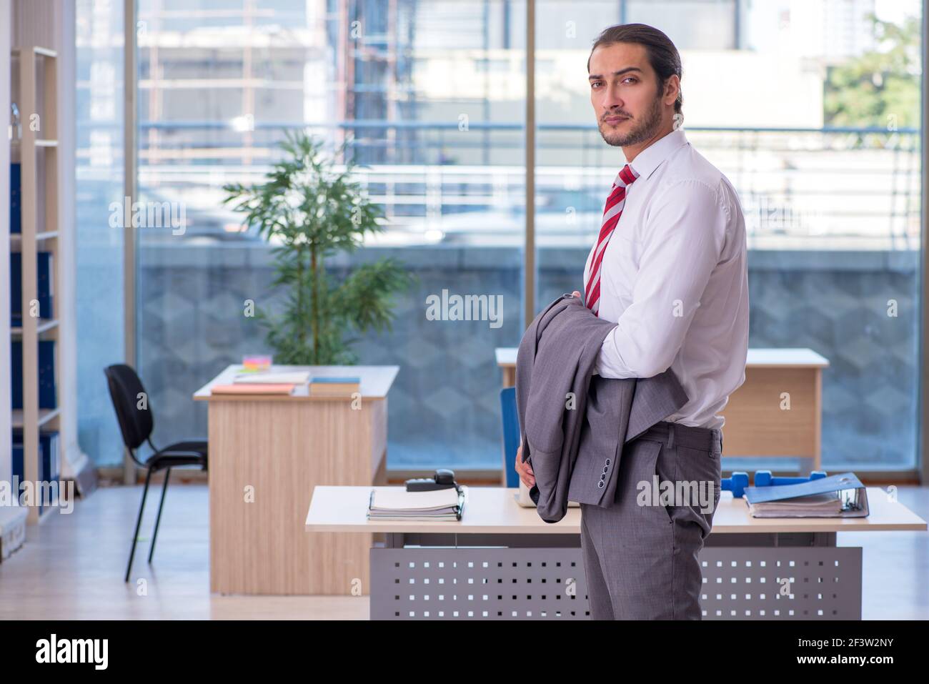 Young employee doing sport exercises at workplace Stock Photo - Alamy