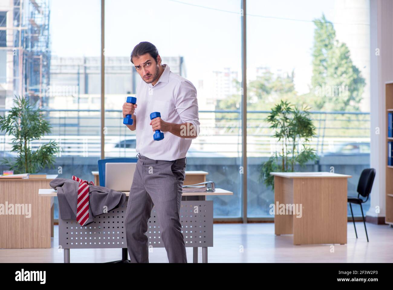 Young employee doing sport exercises at workplace Stock Photo - Alamy