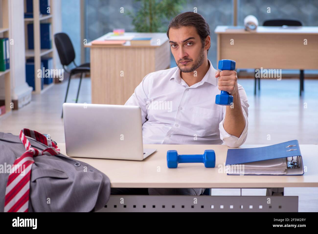 Young employee doing sport exercises at workplace Stock Photo - Alamy