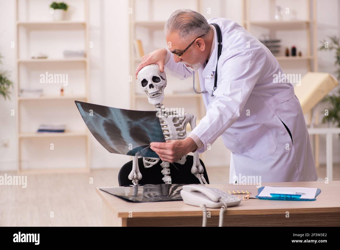 Skeleton patient visiting old male doctor radiologist Stock Photo - Alamy