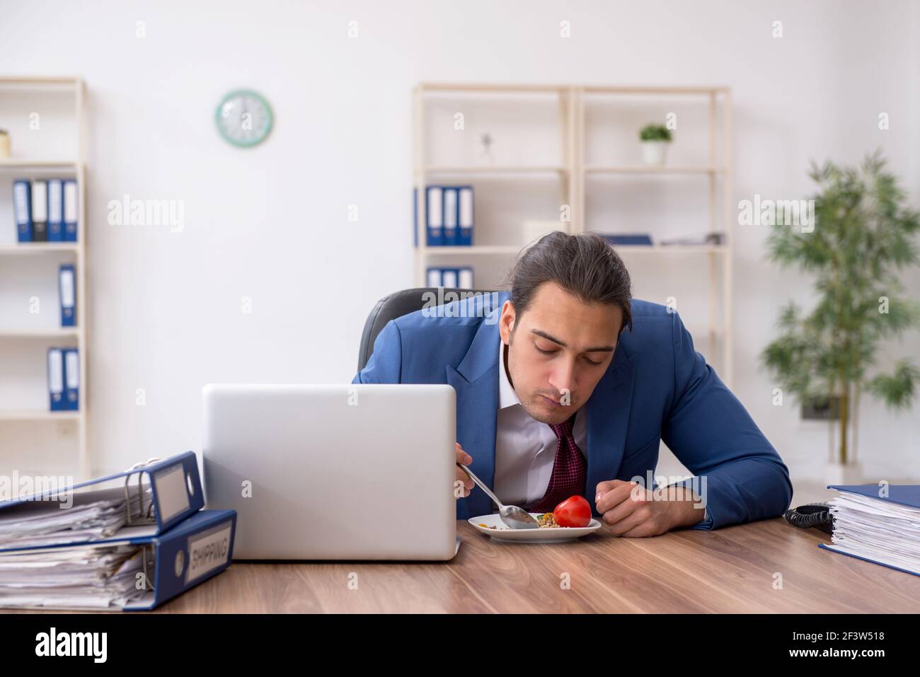 Hungry employee eating buckwheat during break Stock Photo - Alamy