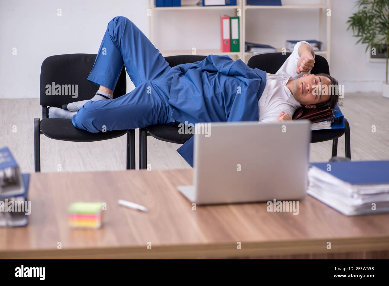 Young employee sleeping in the office on chairs Stock Photo - Alamy