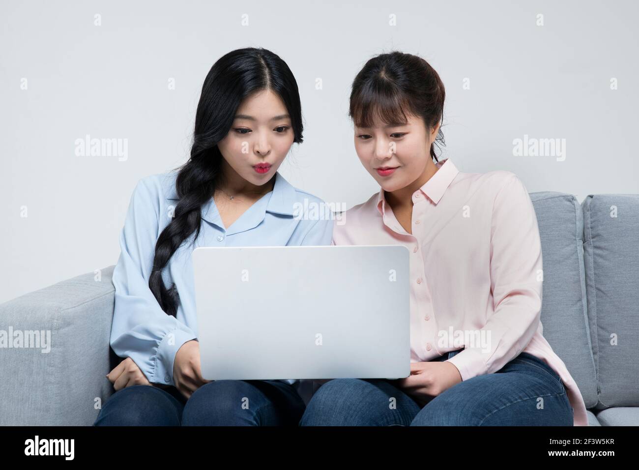 two Asian sisters, women on sofa using laptop Stock Photo - Alamy