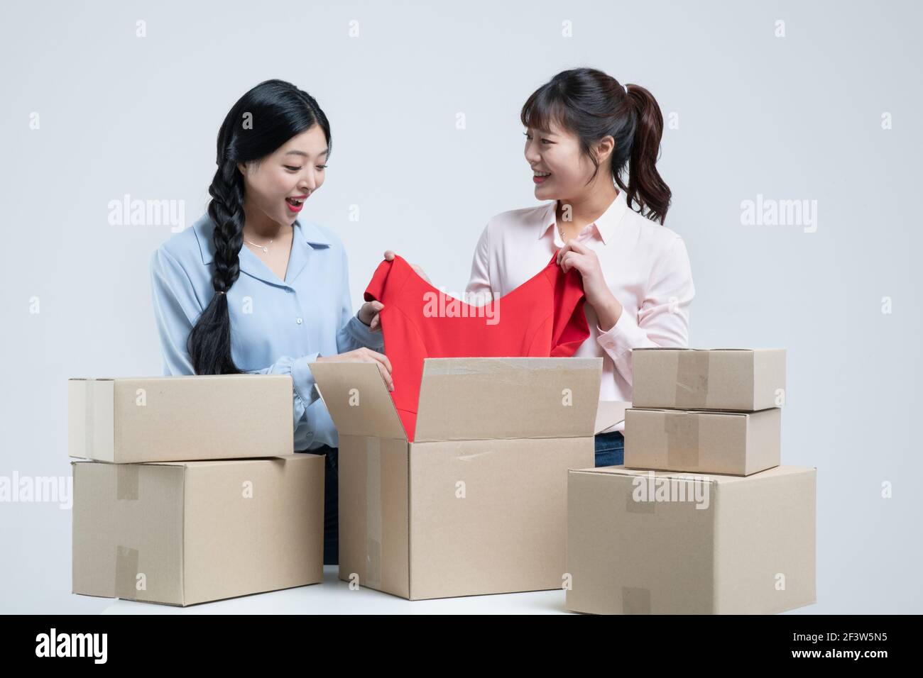 two Asian women, sisters unboxing delivery box on floor Stock Photo - Alamy