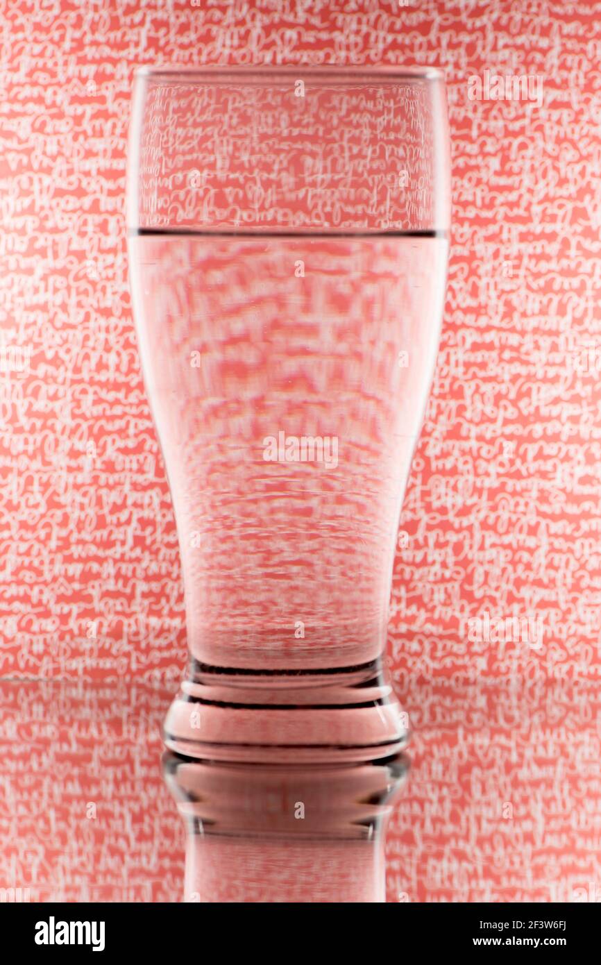 refraction of light by a glass on a red and white background. Abstract ...
