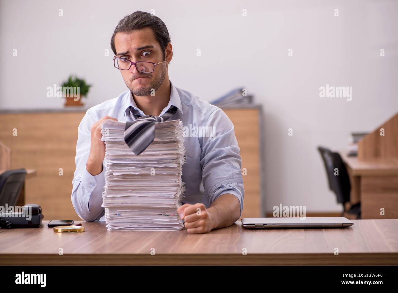Young employee unhappy with excessive work in the office Stock Photo ...