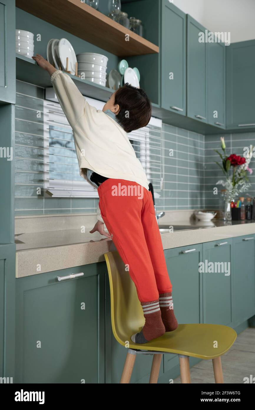 Asian child trying to cook alone in the kitchen Stock Photo - Alamy