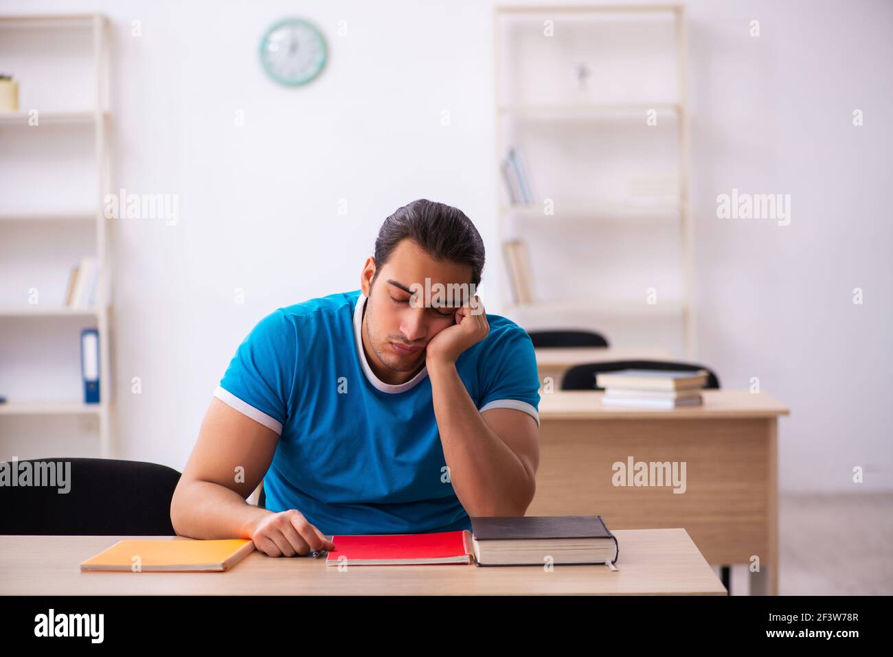 Exhausted student preparing for the exams in the classroom Stock Photo ...