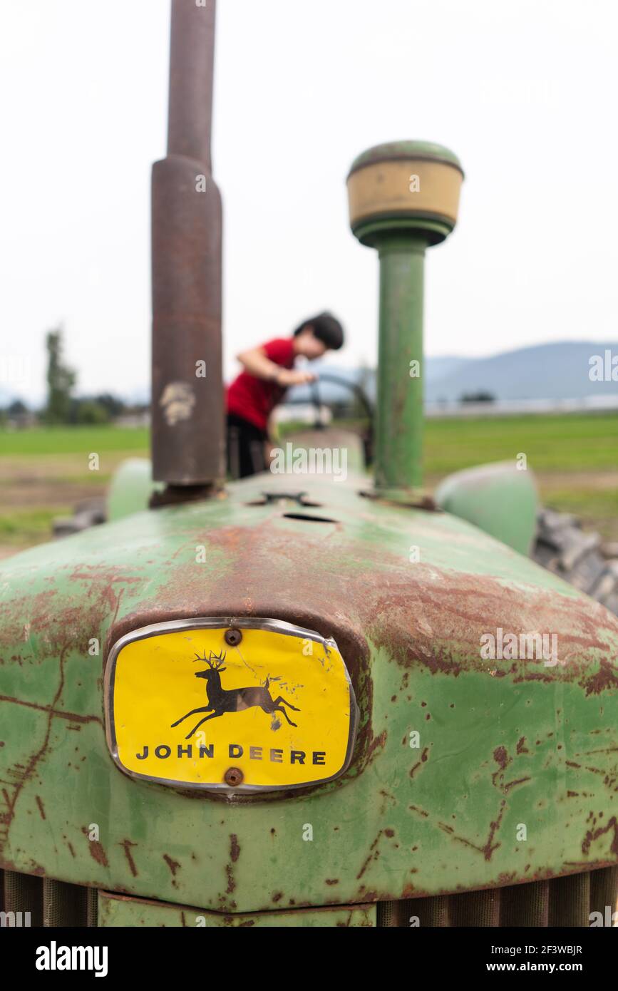 boy climbing onto an old rusty John Deere farm tractor Stock Photo - Alamy