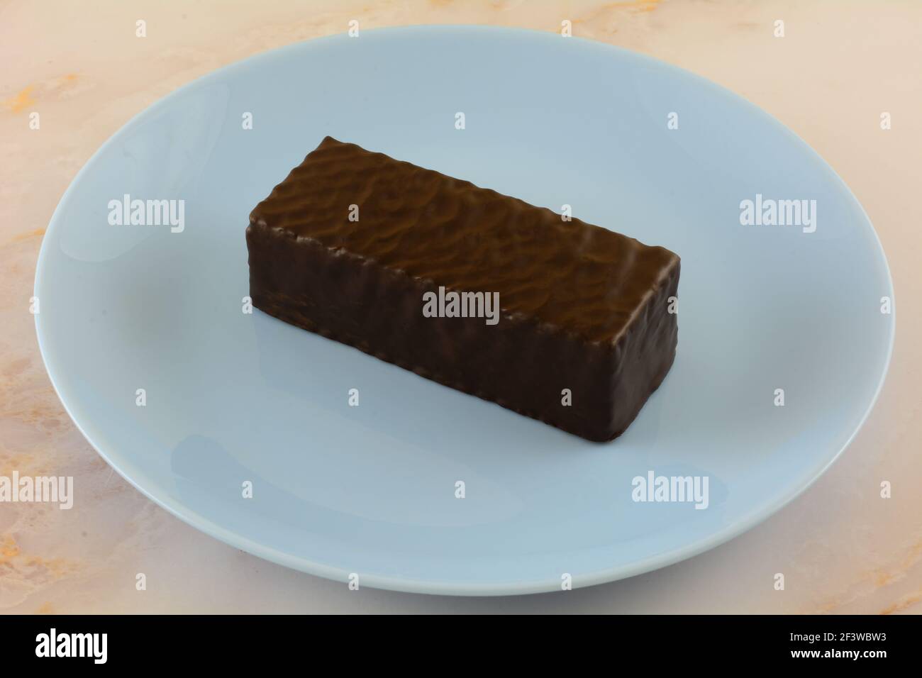 Dark chocolate almond wafer candy bar snack on small blue dessert plate ...