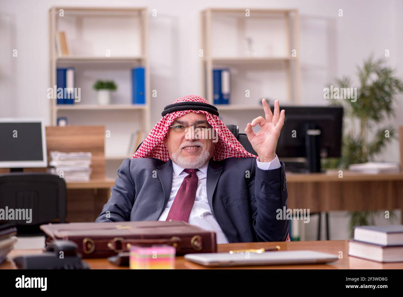 Old male arab employee sitting at workplace Stock Photo - Alamy