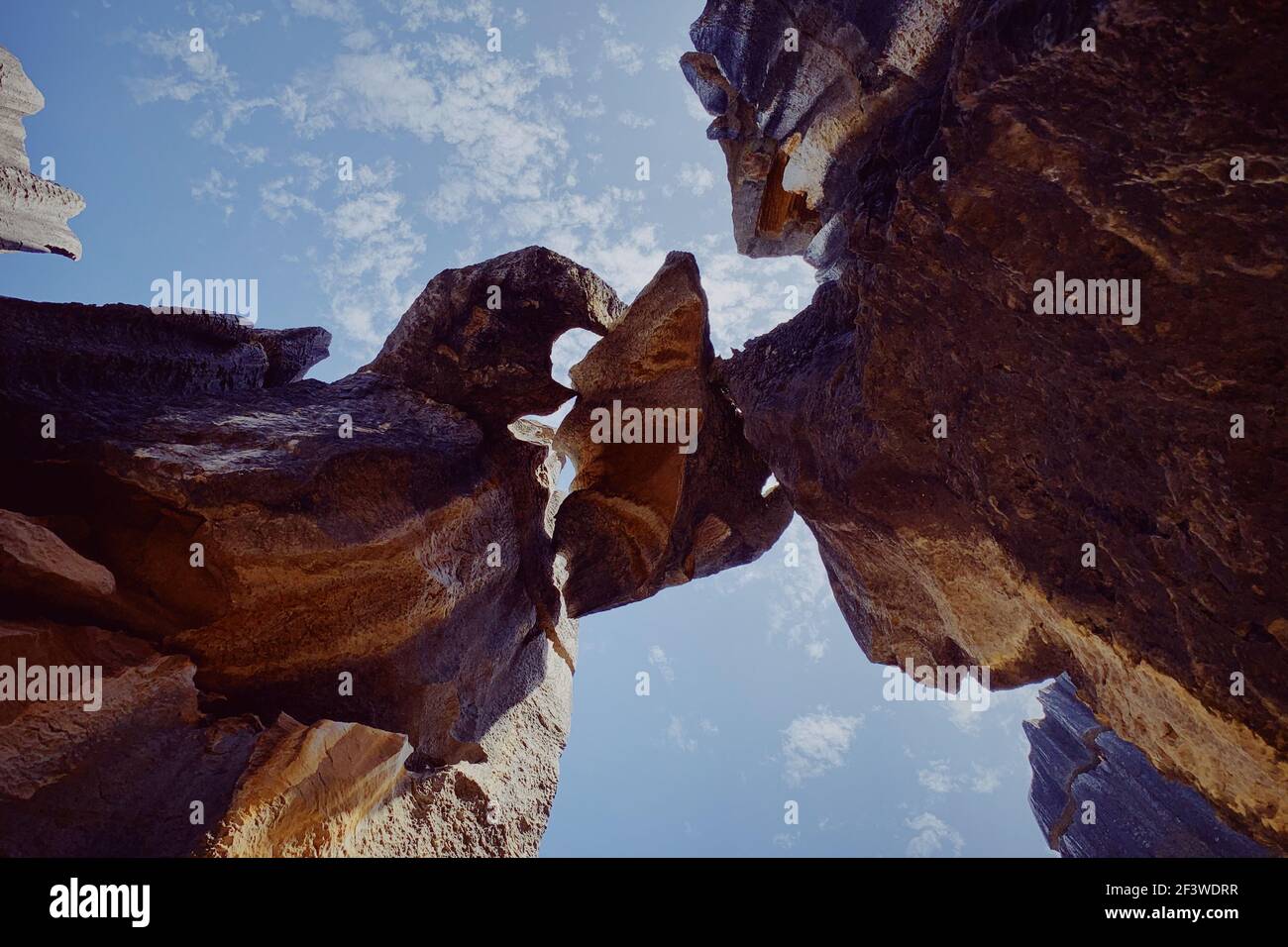 A worm's eye view of a boulder between rock pillars against a blue sky ...
