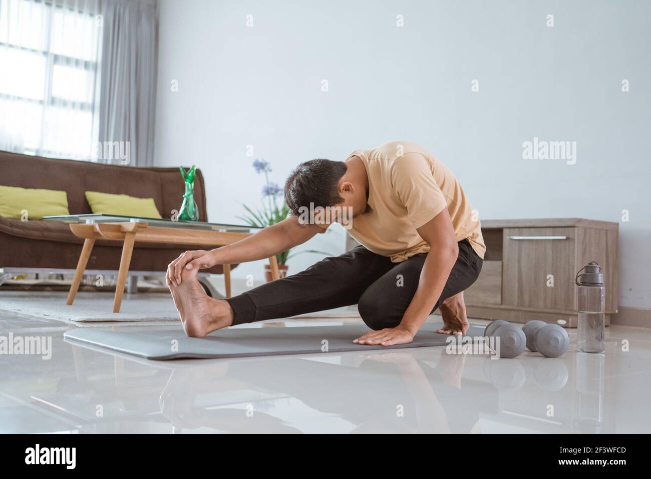 asian Fit Young Man Exercise Mat While Lifting One Leg and Looking to ...