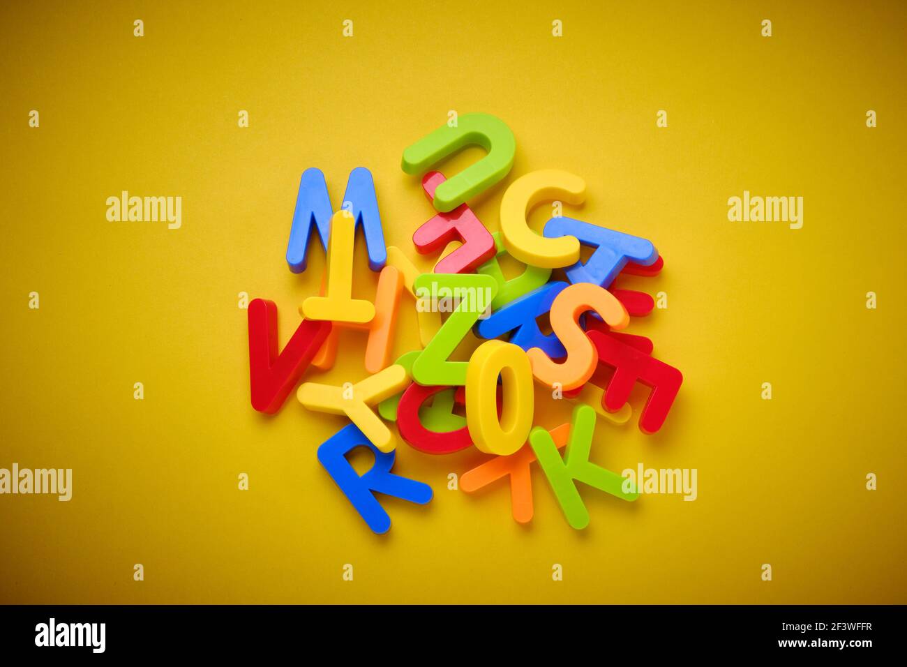 Colorful plastic letters messed up on yellow background Stock Photo - Alamy