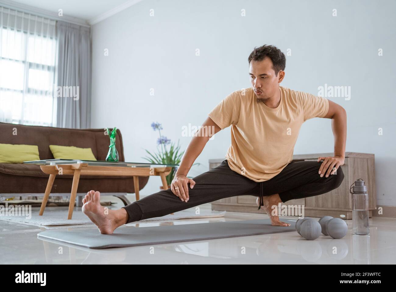 asian Fit Young Man Exercise Mat While Lifting One Leg and Looking to ...