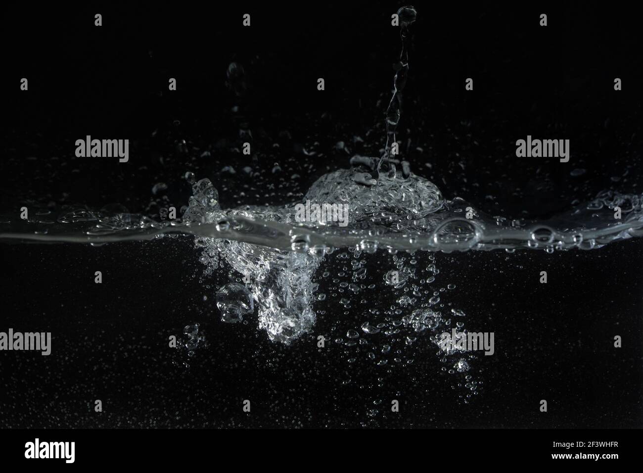 Water splashing as it's poured into aquarium tank, black background ...