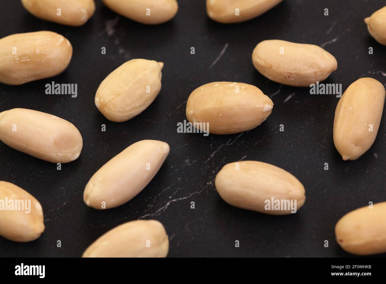 Group of peeled peanuts on black marble like board, closeup detail from ...