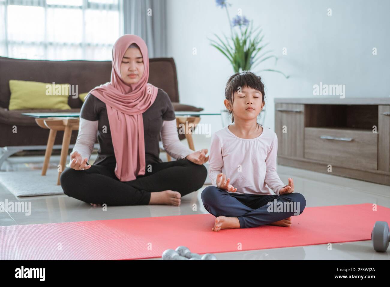 muslim woman and daughter doing yoga exercise and sport at home ...