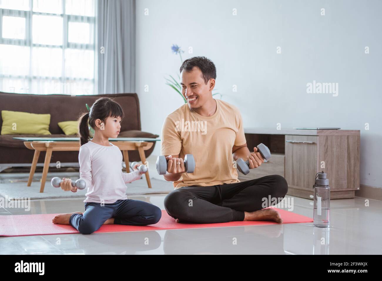 kid and his dad doing exercise weight lifting at home together Stock ...