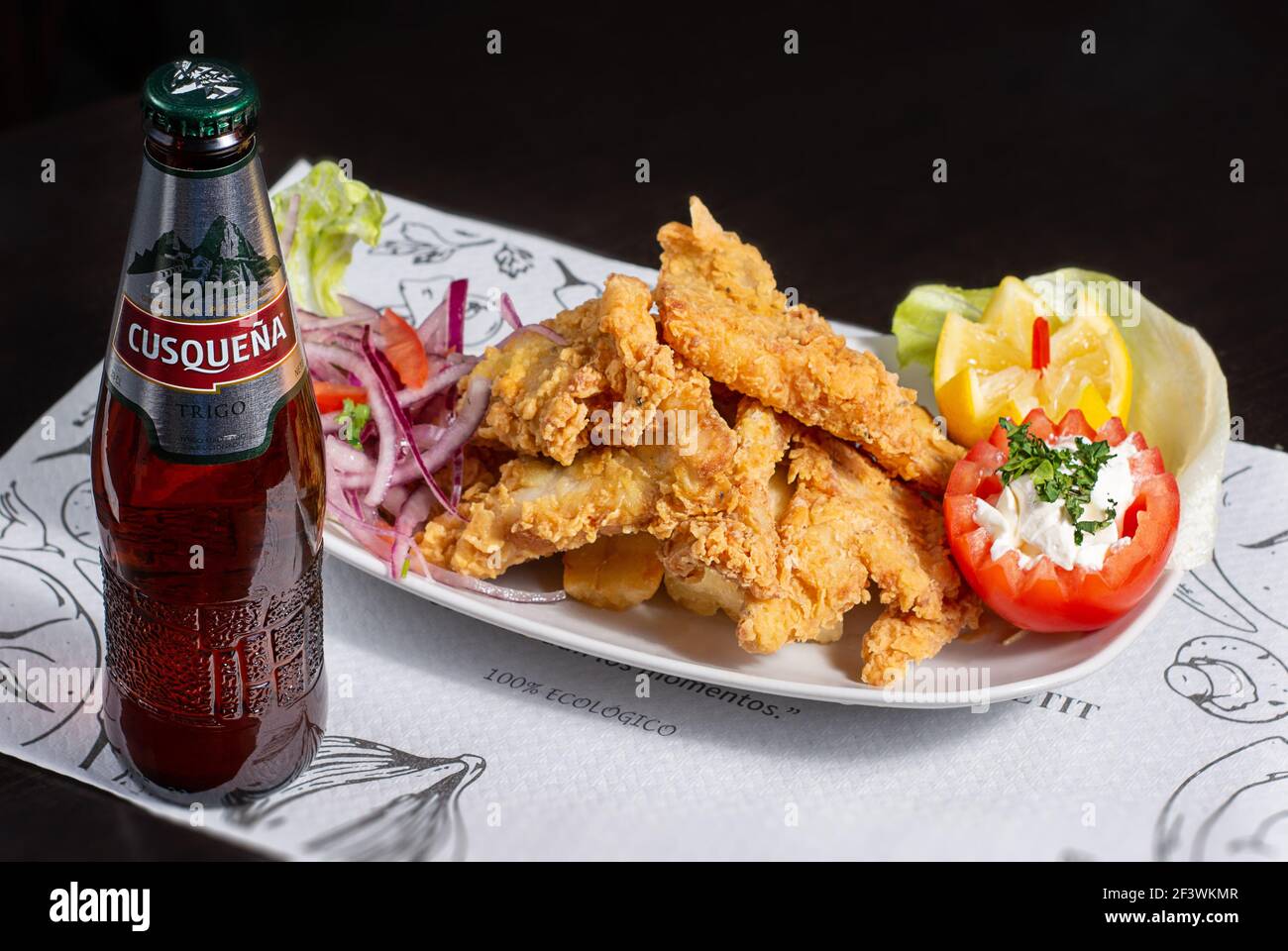 Cusco, Peru, 28.02.2021. Peruvian beer Cusquena and fried fish dish ...