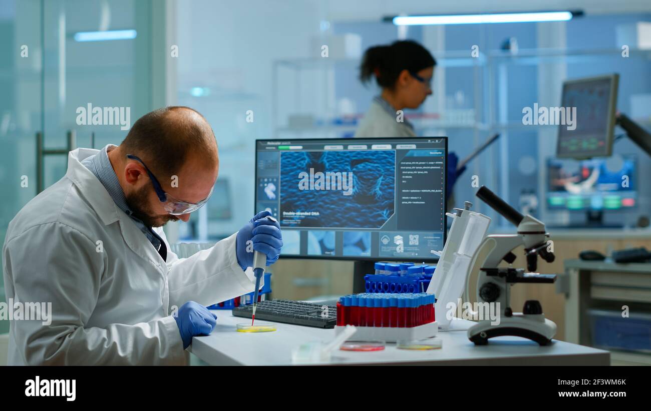 Man scientist using micropipette for filling test tubes in modern ...