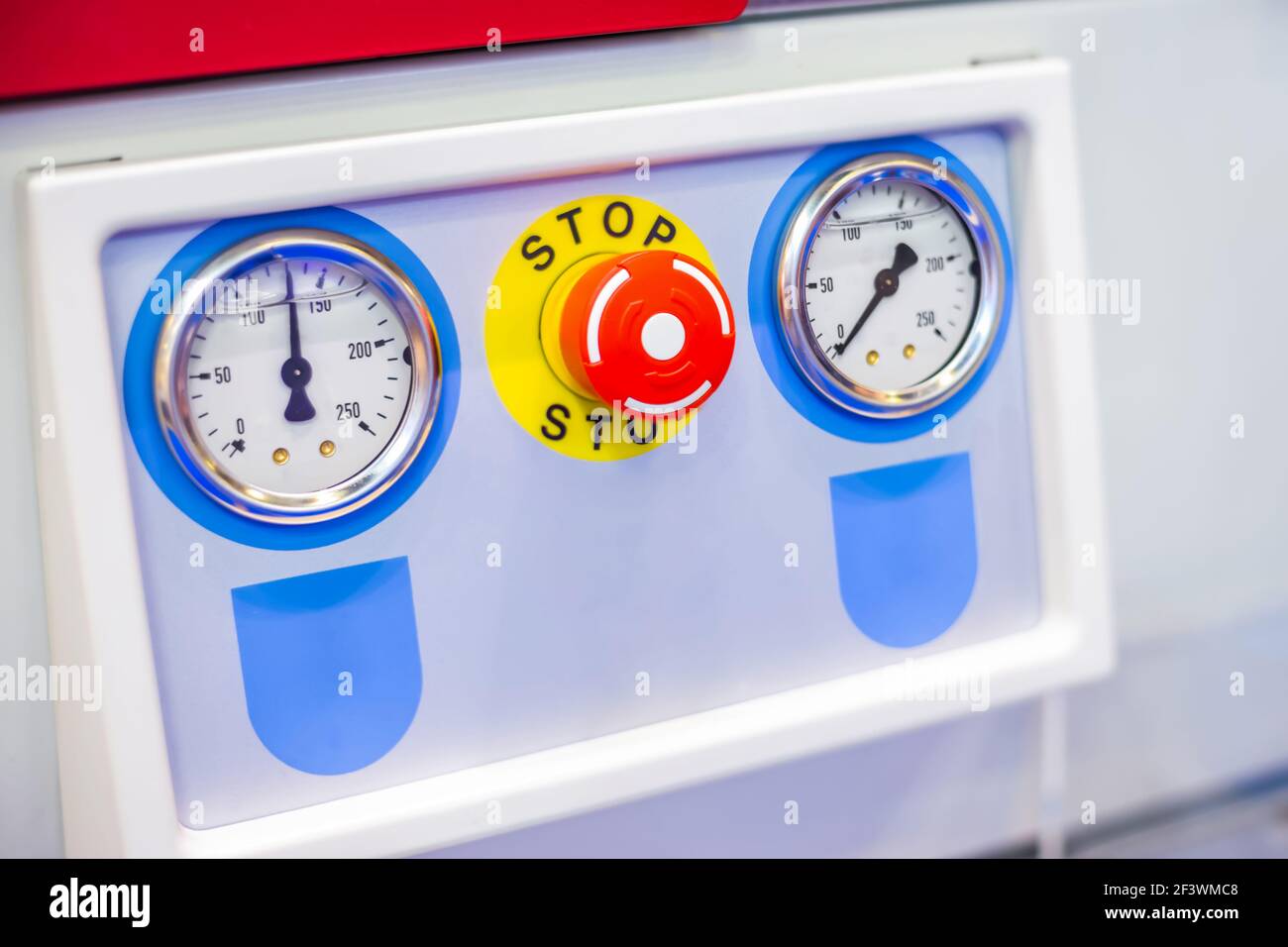 Machine control panel with red push stop button and pressure gauge at ...