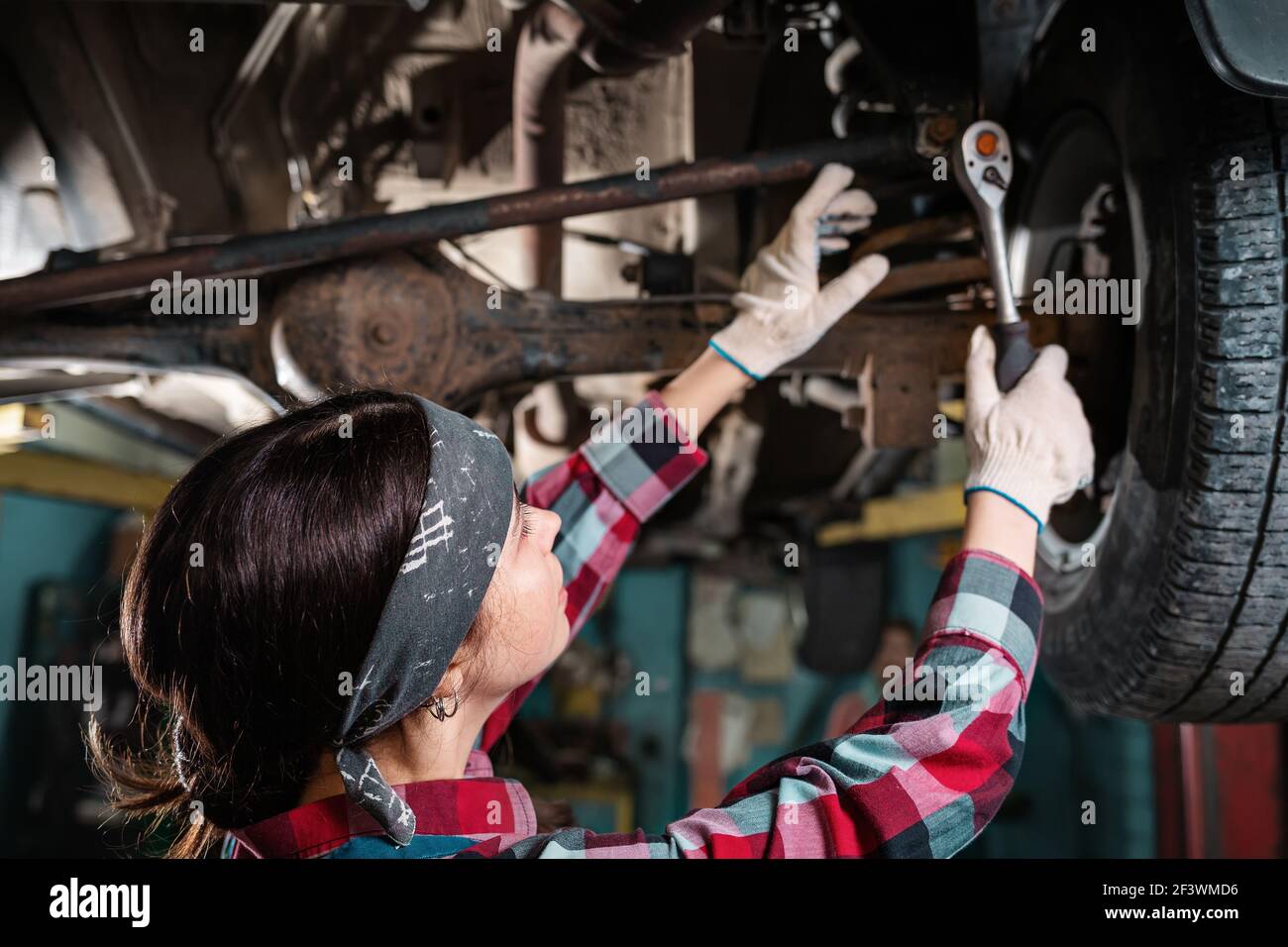 Portrait of a young female mechanic, unscrewing nuts with a wrench ...