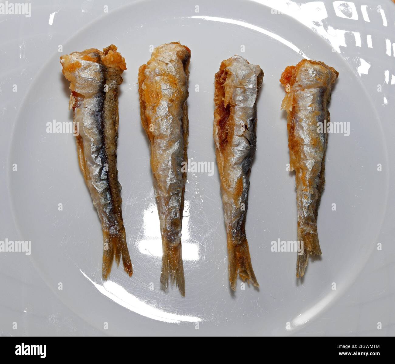 Close up of four fried anchovies in a dish. Greek traditional dish ...