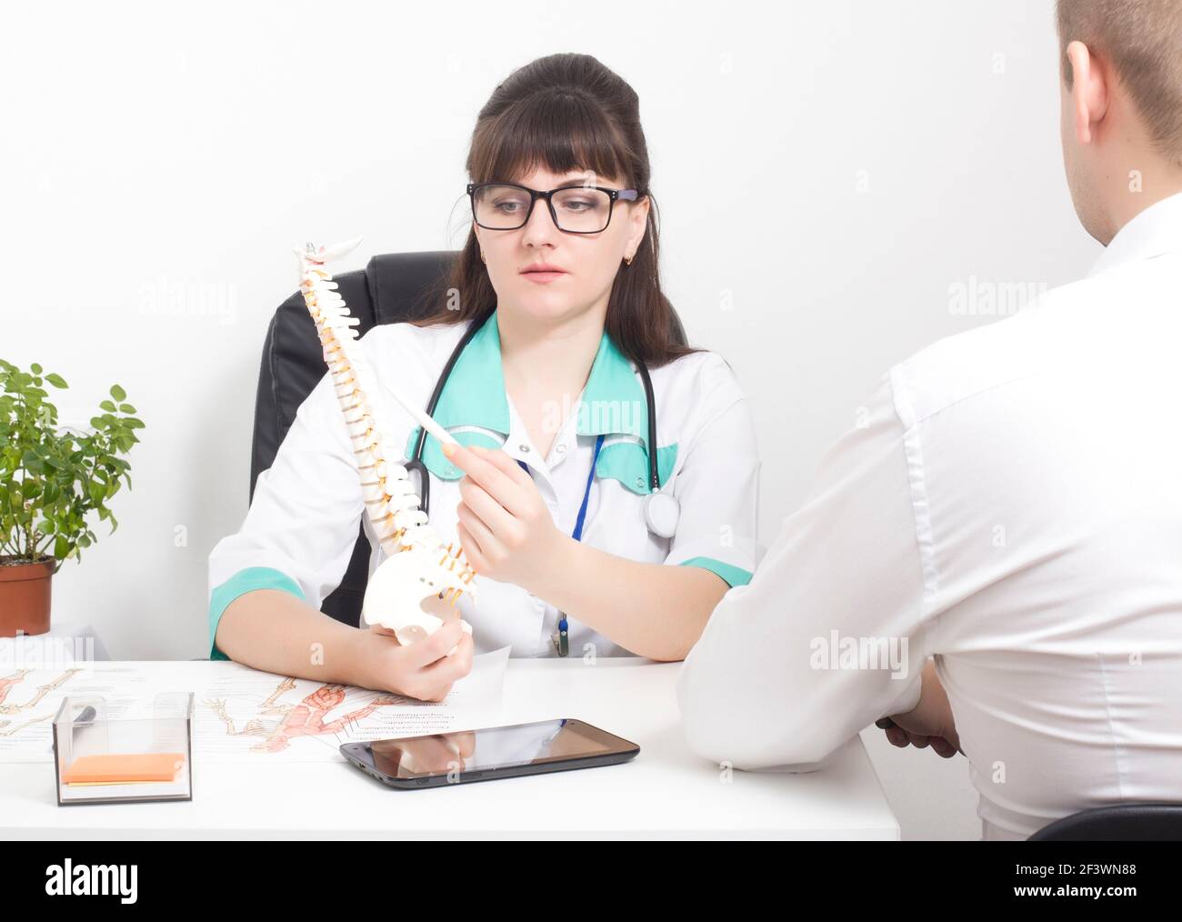 The doctor explains to the patient on the layout of the spine how the ...