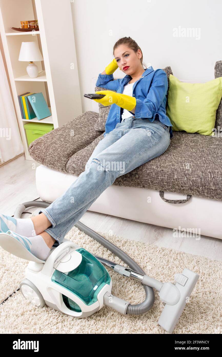 Tired woman watching television at home after vacuuming Stock Photo - Alamy