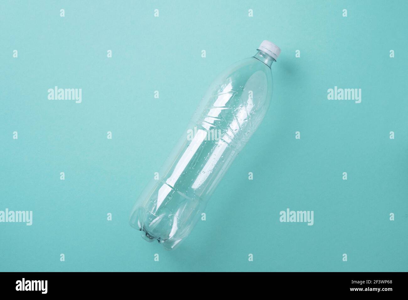 Empty rumpled used plastic bottle on blue background. Top view, copy ...