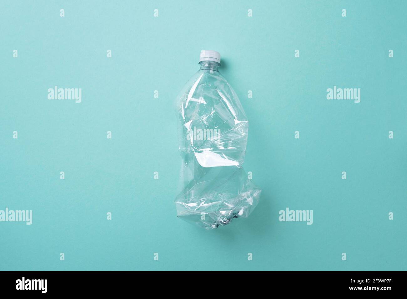 Empty rumpled used plastic bottle on blue background. Top view, copy ...