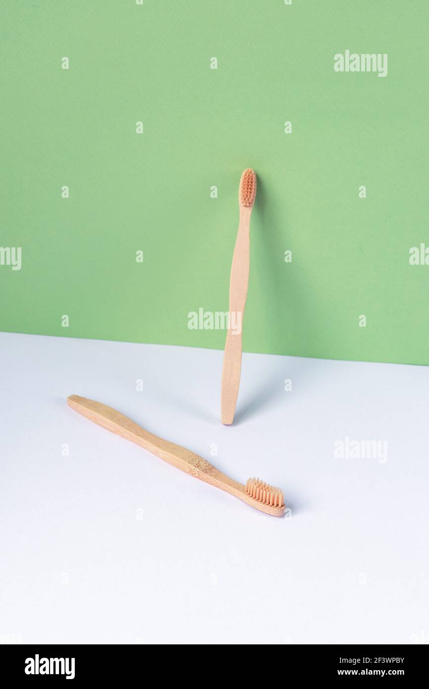 Two toothbrushes on a white table against a green wall. Personal ...