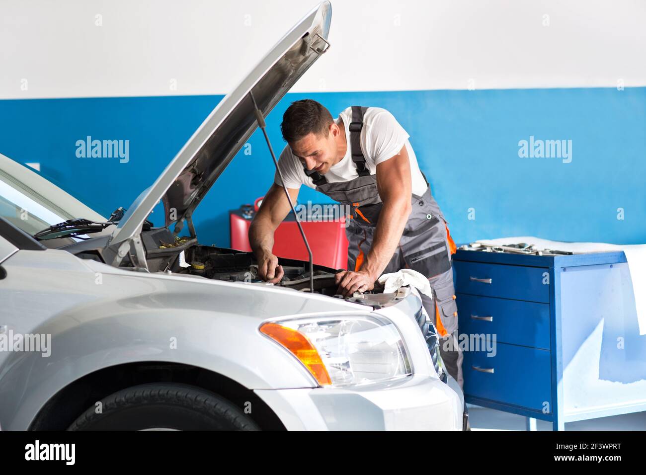 Mechanic repairing a lifted car at garage Stock Photo - Alamy