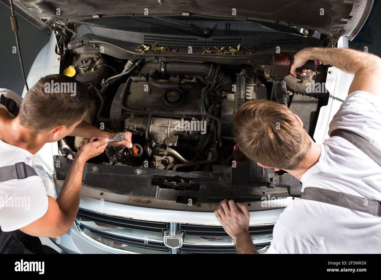 Working together on a car engine in workshop Stock Photo - Alamy