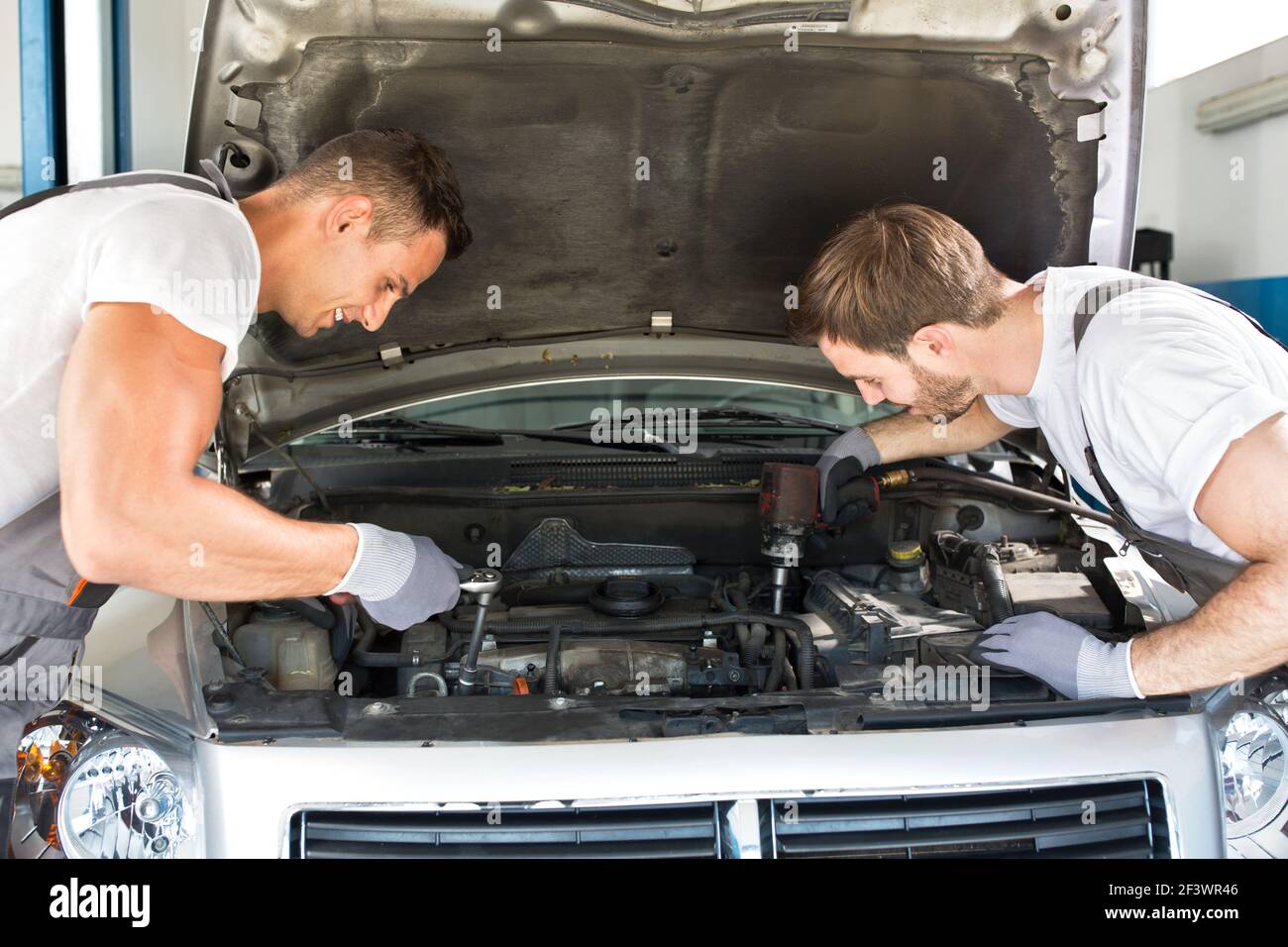 Mechanics fixing a car with tools in workshop, success teamwork Stock ...