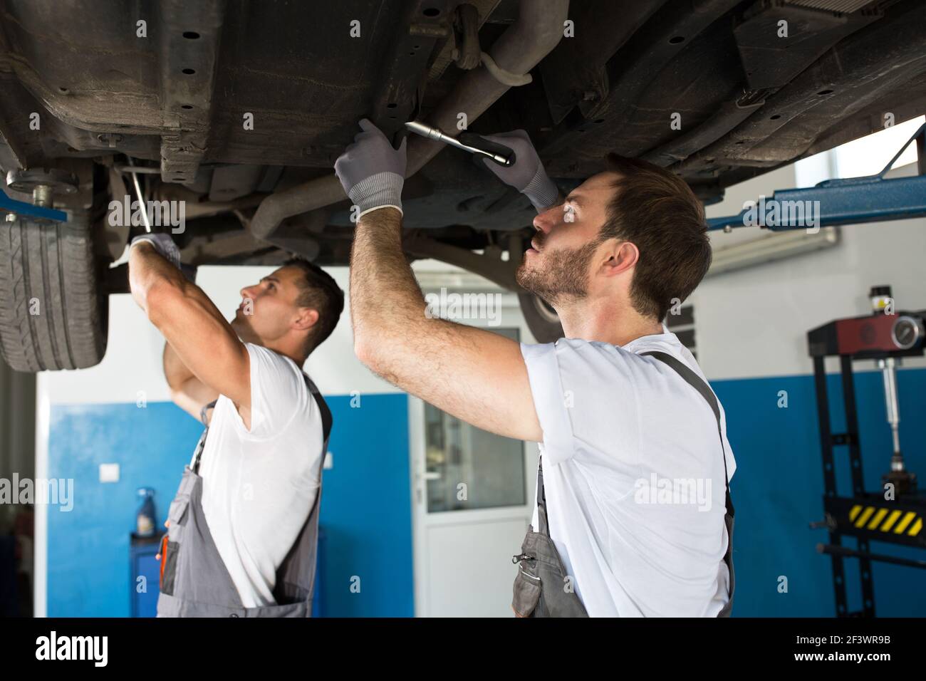 Mechanics working together under the car with a tools and repair car ...