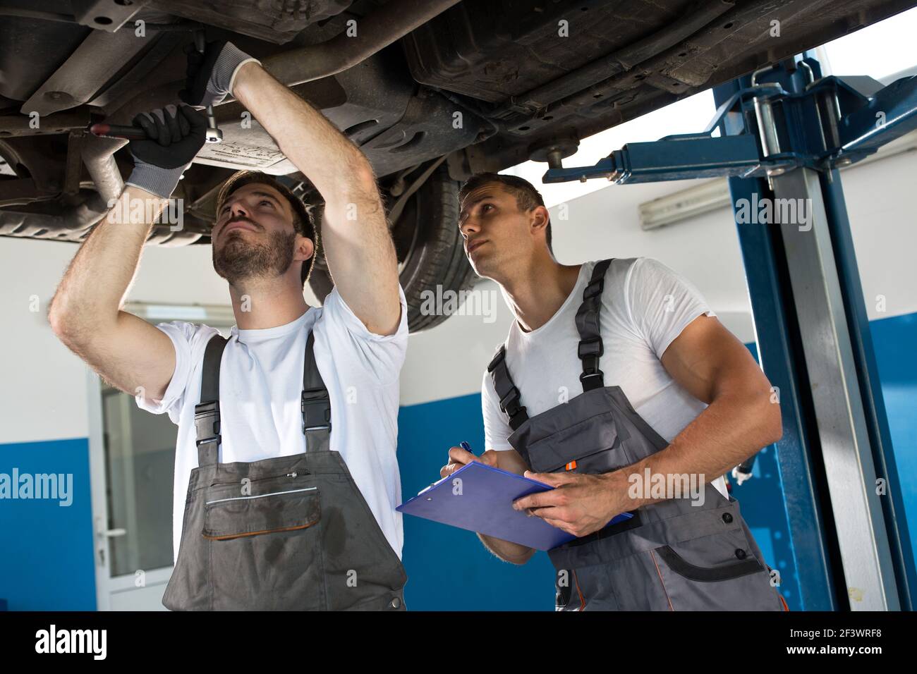 Mechanics teamwork in a workshop cheking and repair car Stock Photo - Alamy