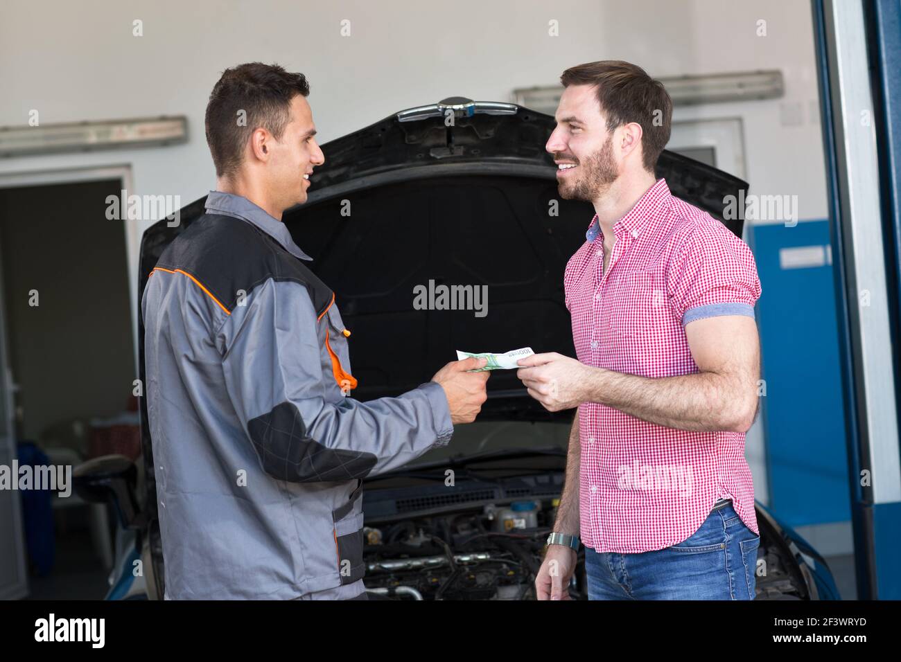 Satisfied customer pays the repair of the car Stock Photo - Alamy