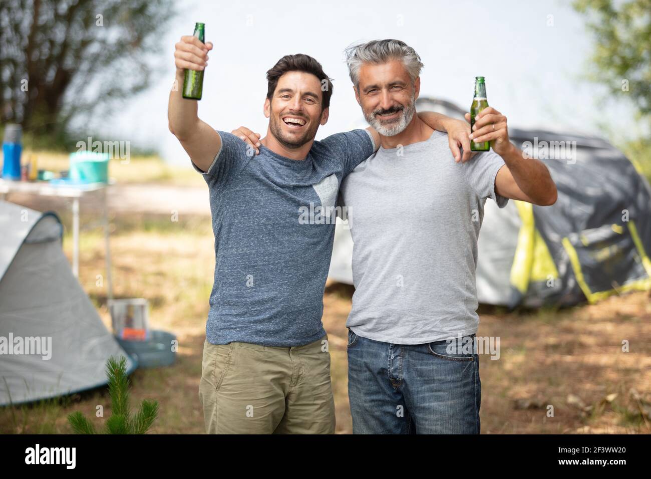 happy men drinking beer at campsite tent Stock Photo - Alamy