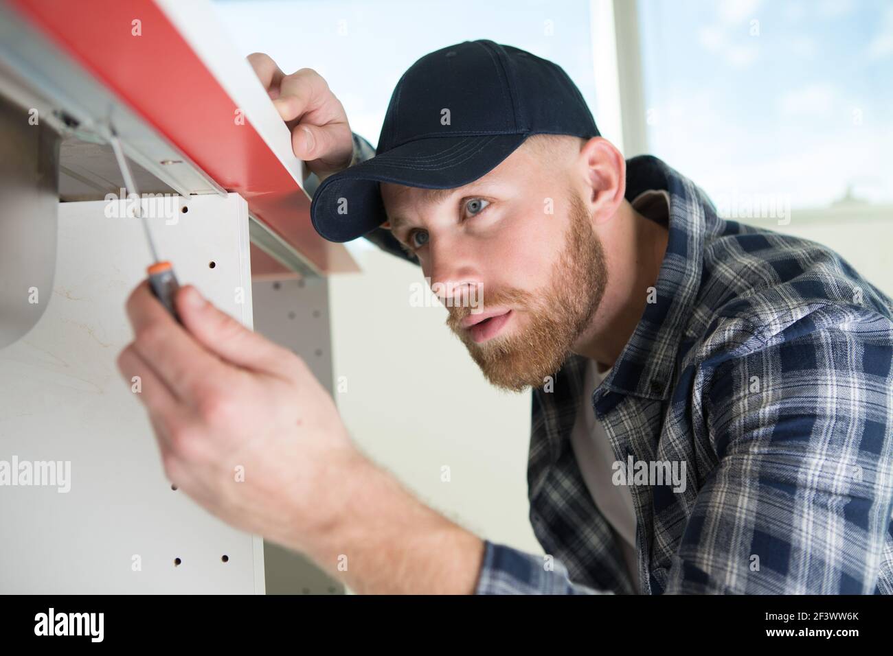 man assembling kitchen cupboard using screwdriver Stock Photo - Alamy