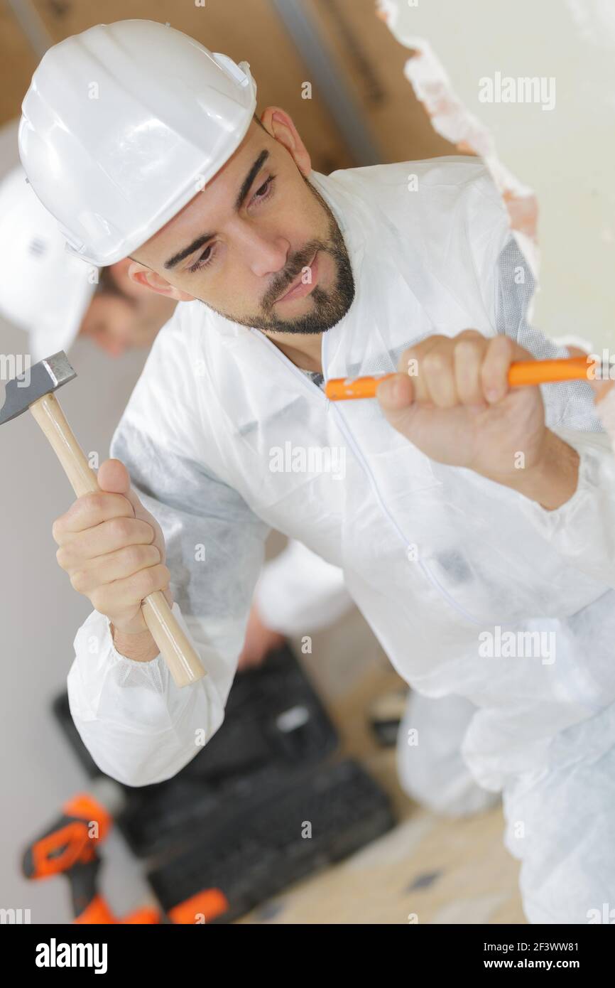young man contactor with a chisel and hammer Stock Photo - Alamy