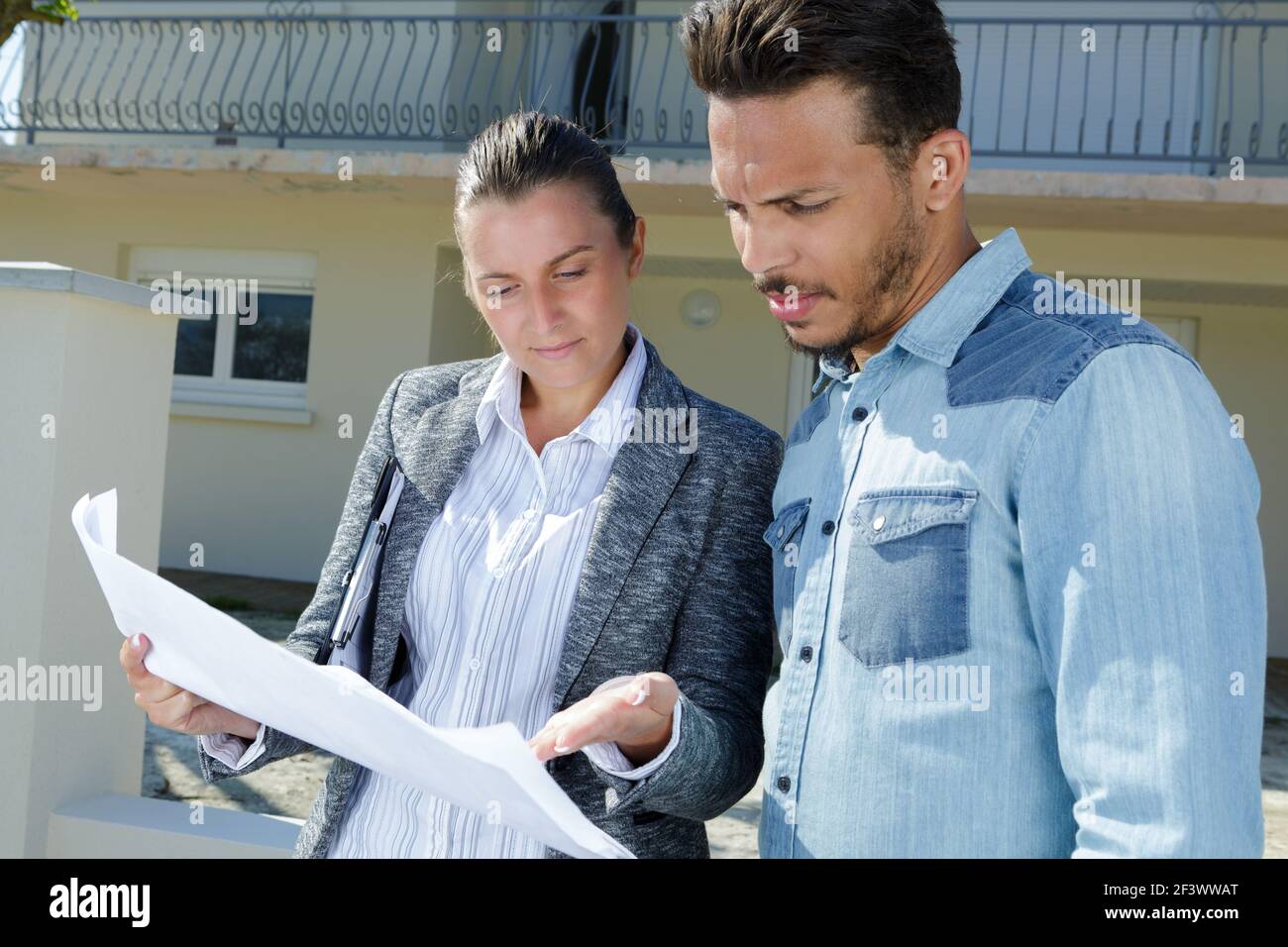 real estate agent showing property blueprint to client Stock Photo - Alamy