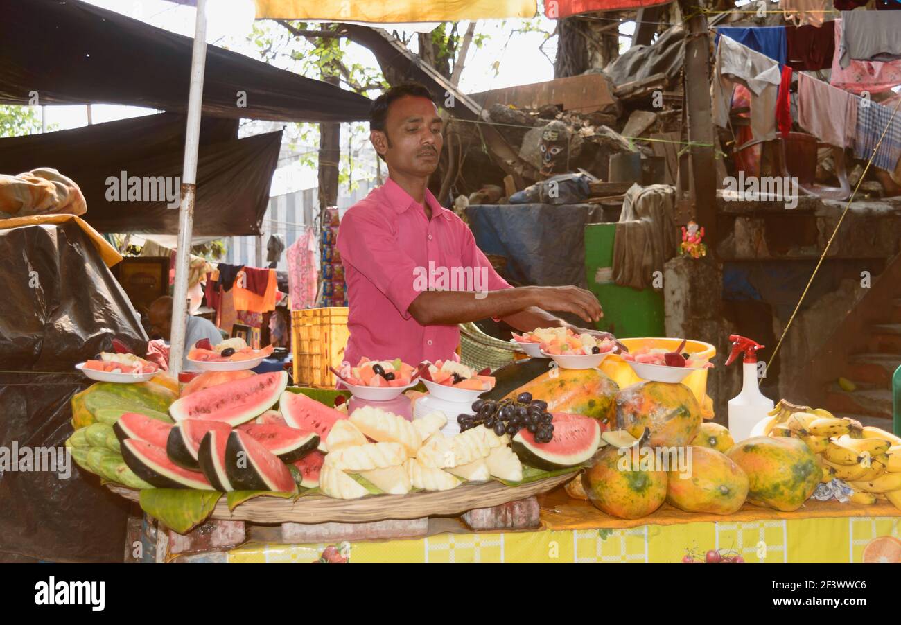A man selling Fresh prepared fruits cut in pieces in his street food ...