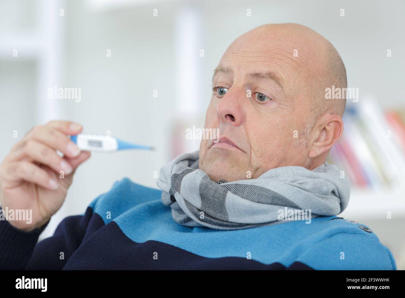 man on sofa checking his body temperature with thermometer Stock Photo ...