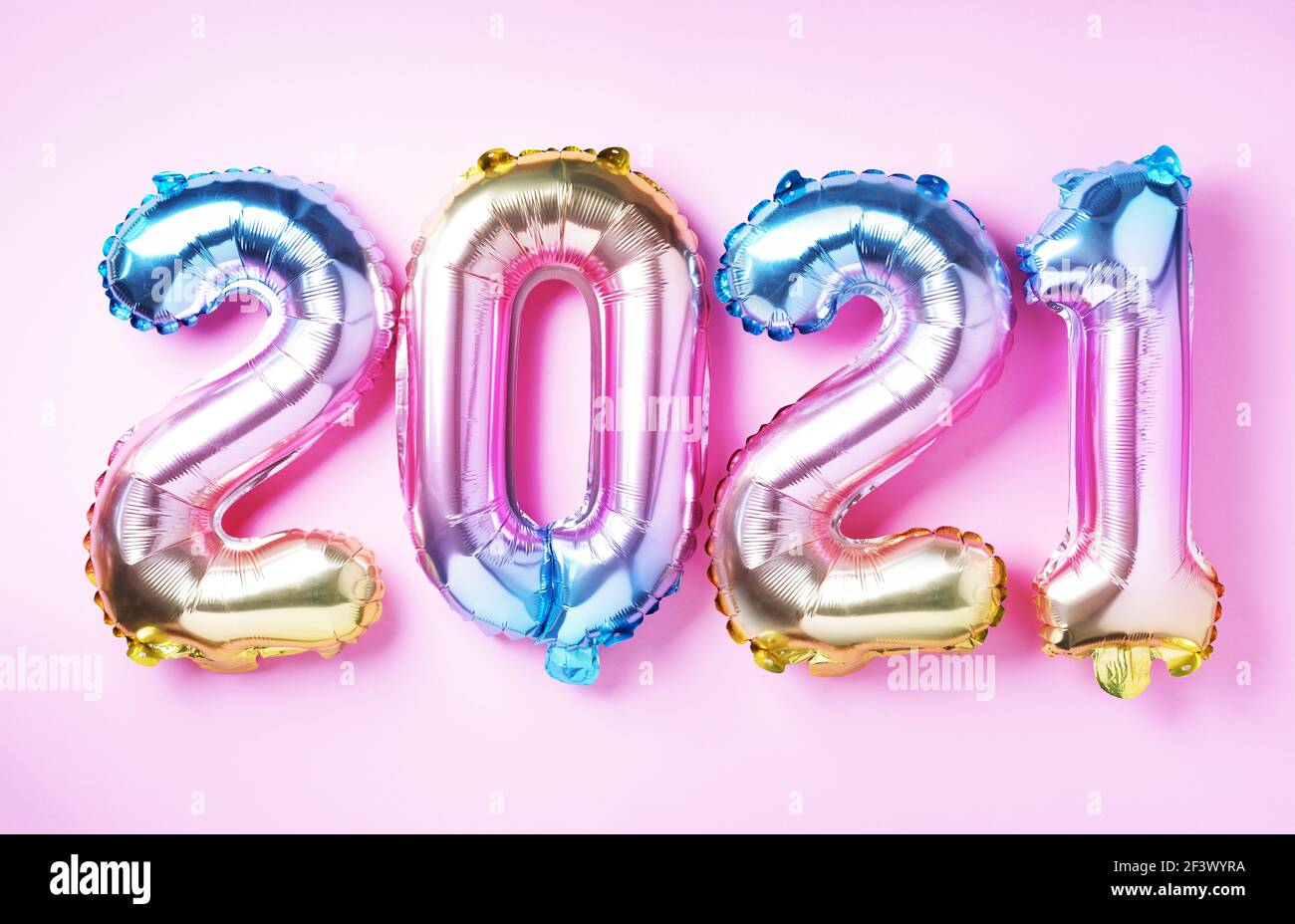Colorful foil balloons made numbers 2021 on pink background with light ...