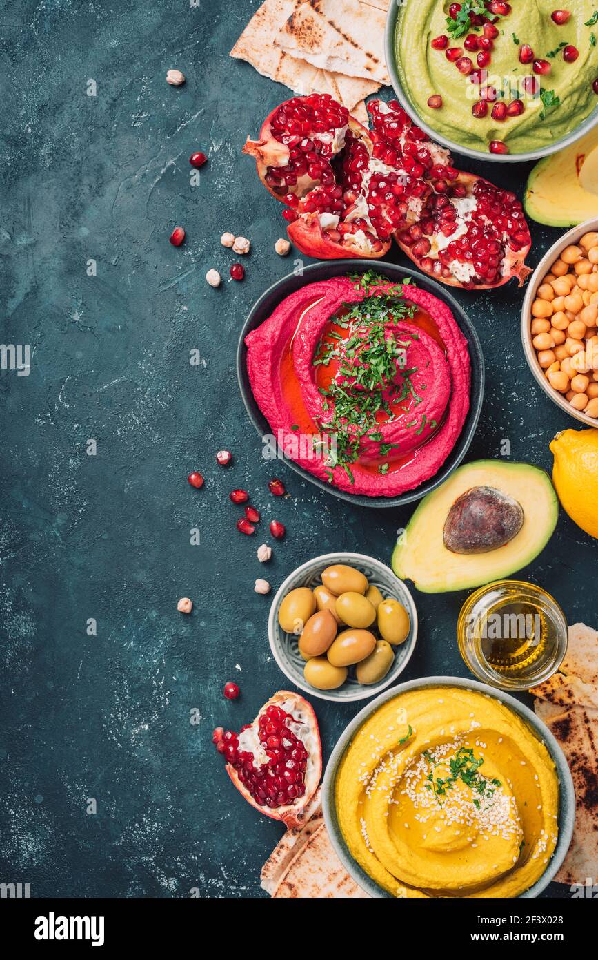 Colorful hummus bowls - green, yellow and beetroot hummus on dark ...