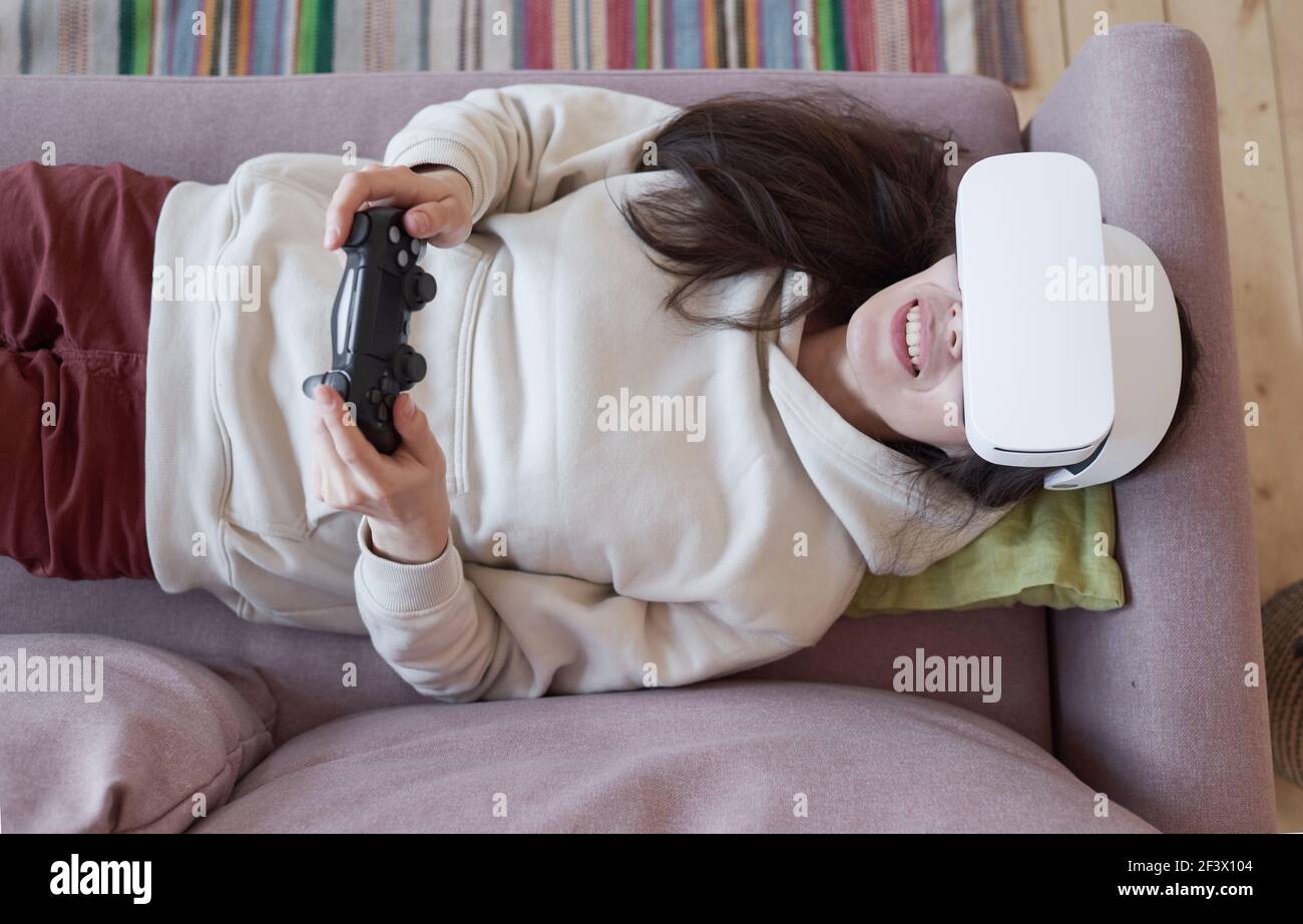 High angle view of woman lying on sofa in virtual reality headset with ...